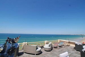 Um terraço com mobiliário de vime e vista para o oceano.