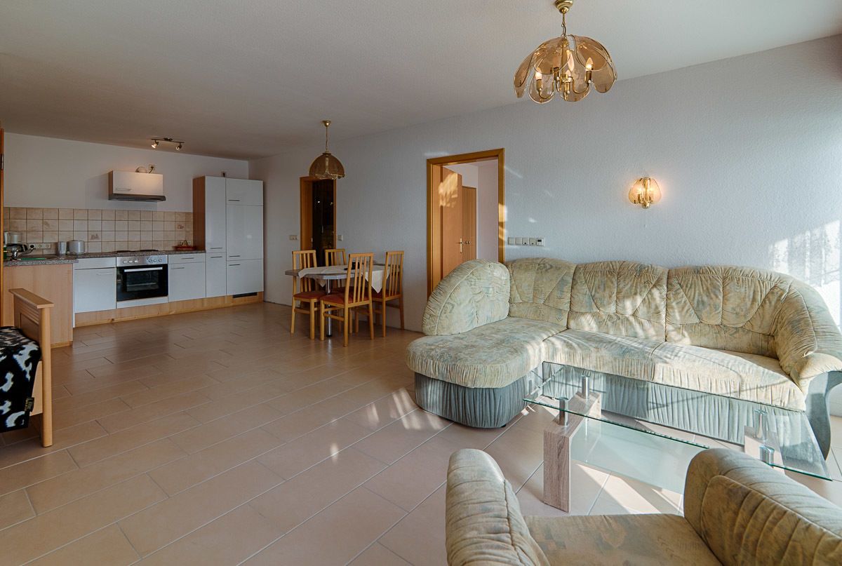 Uma sala de estar moderna com um sofá modular, uma mesa de centro de vidro e uma área de jantar com cadeiras de madeira.