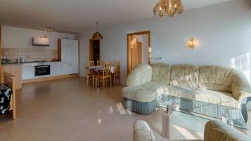 Uma sala de estar moderna com um sofá modular, uma mesa de centro de vidro e uma área de jantar com cadeiras de madeira.