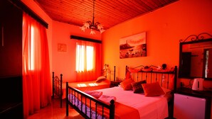 Quarto com cama, mesa de cabeceira, cômoda, espelho e janela com cortinas.
