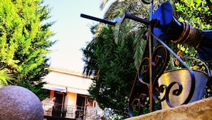 Um pátio com uma escultura de metal, cactos e um edifício com varandas ao fundo.
