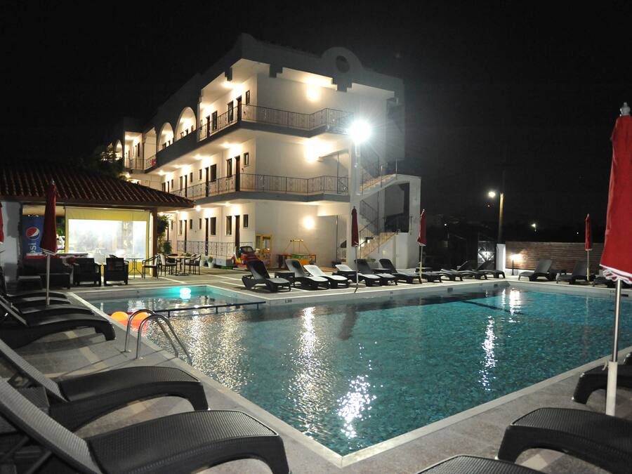 Piscina com espreguiçadeiras e um edifício com várias varandas ao fundo.