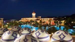 Um hotel com área de piscina, estruturas em cúpula e uma torre.
