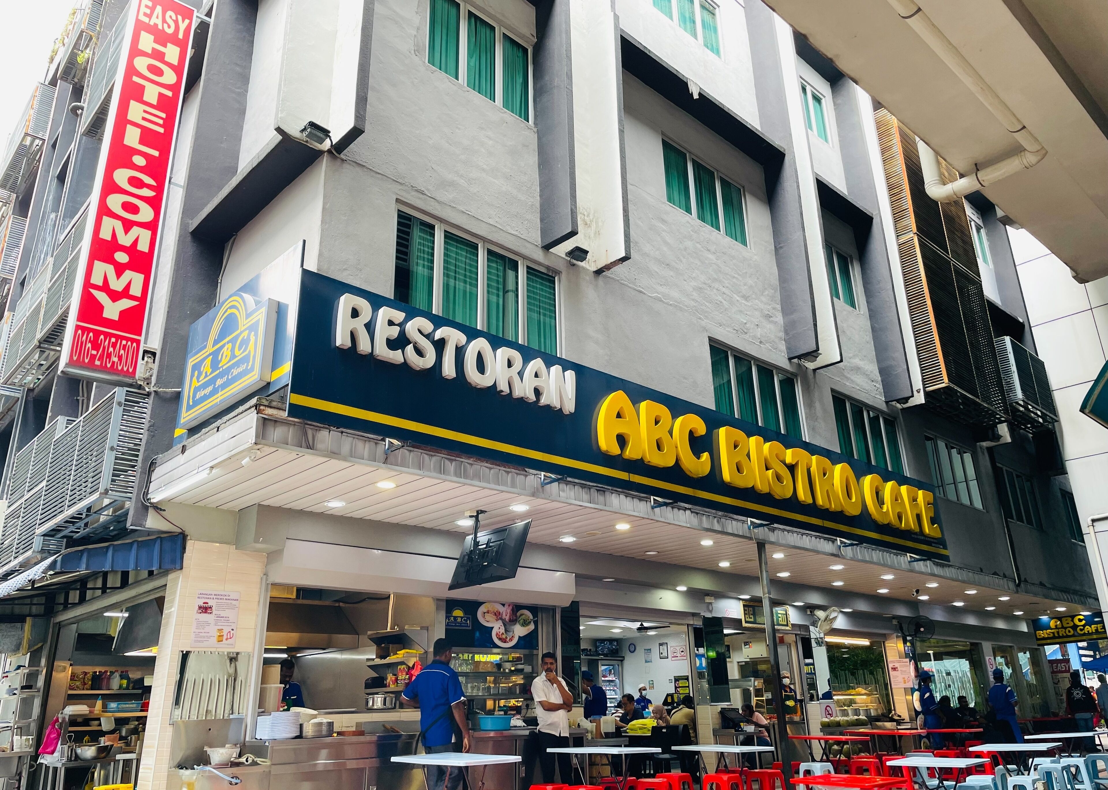 Um restaurante chamado ABC Bistro Cafe, com área de estar ao ar livre visível e uma placa anunciando o restaurante.