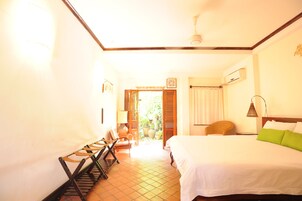 Quarto de hotel com cama, cadeira, luminária e janela.