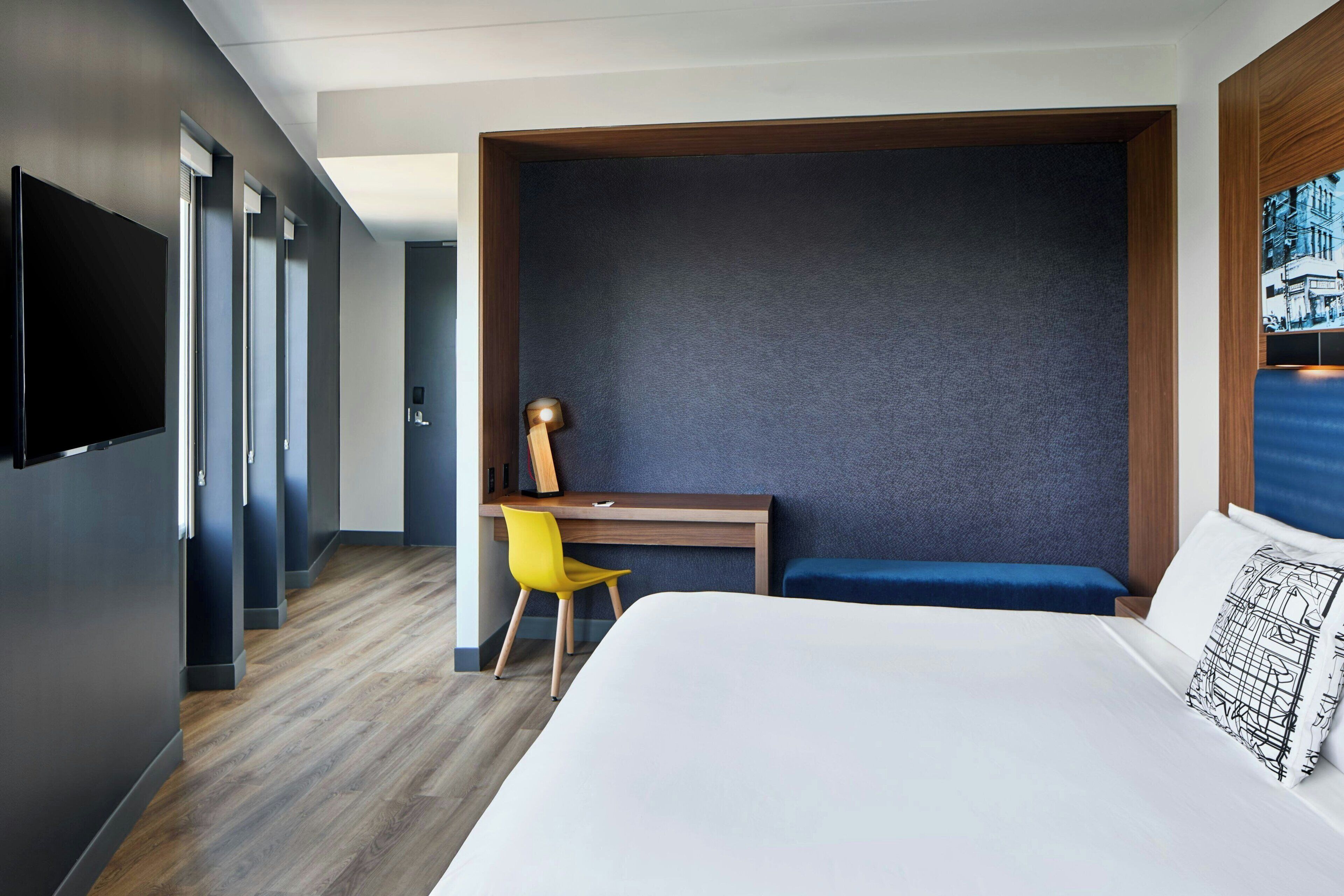 Quarto de hotel moderno com uma cama grande, uma escrivaninha e uma cadeira.
