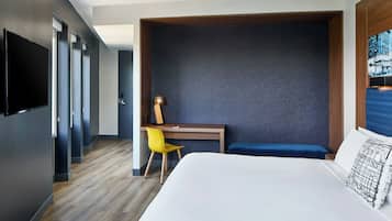 Quarto de hotel moderno com uma cama grande, uma escrivaninha e uma cadeira.