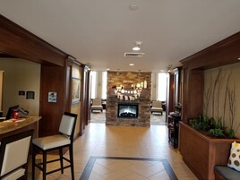 Um lobby de hotel com lareira de pedra, balcão de recepção e área de estar.