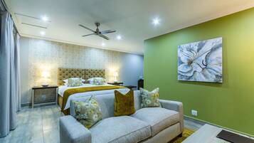 Quarto moderno com cama, sofá, ventoinha no teto e um quadro na parede.