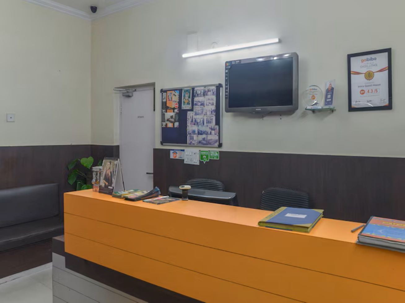 Uma área de recepção com balcão, televisão de tela plana, quadro de avisos e um prêmio emoldurado.