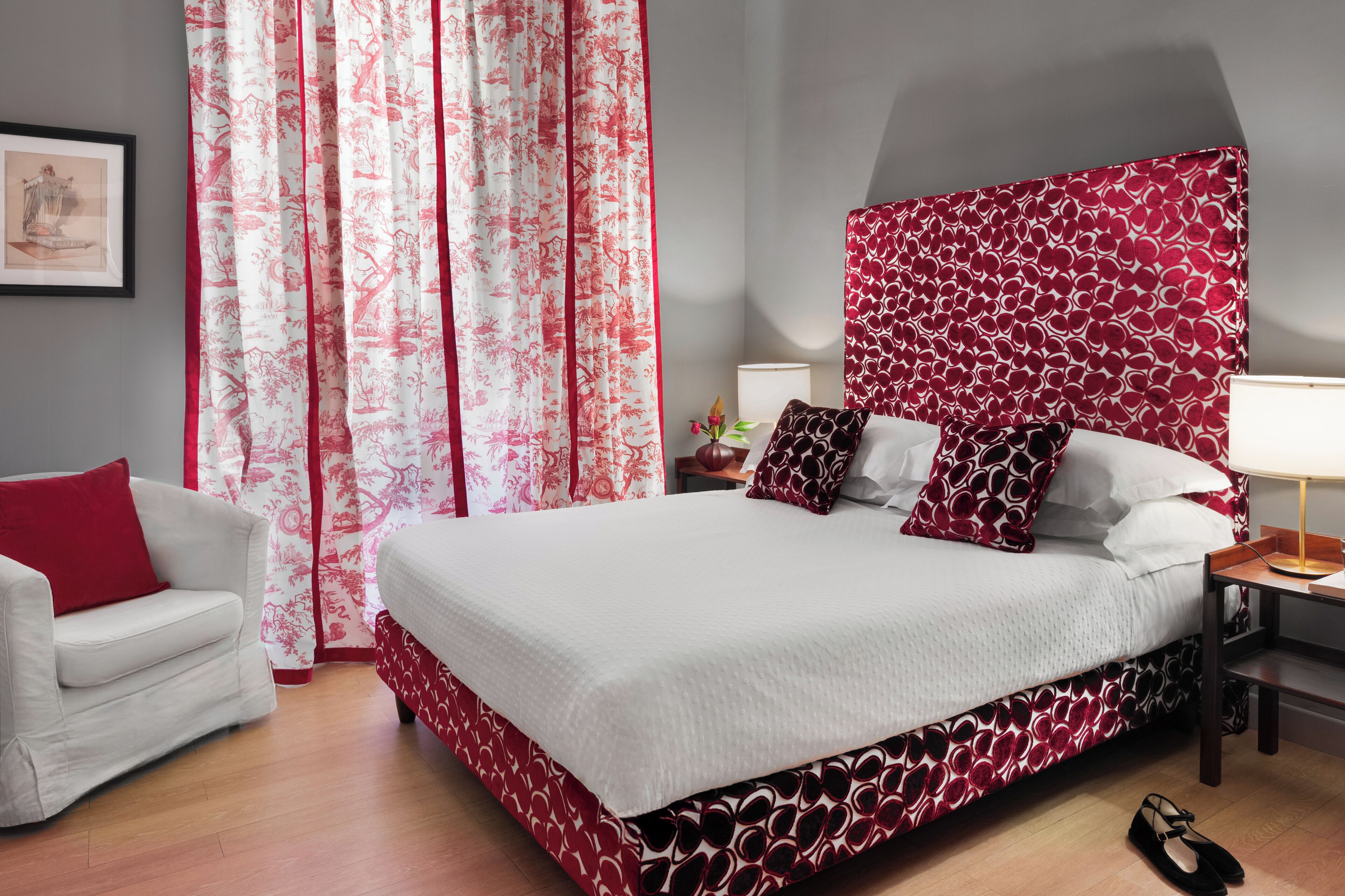 Quarto bem arrumado com uma cama grande, mesa de cabeceira com abajur, cadeira e quadro na parede.