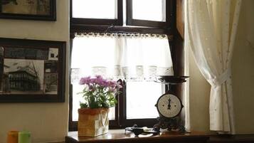 Quarto com janela, relógio, vaso com flores e quadro na parede.