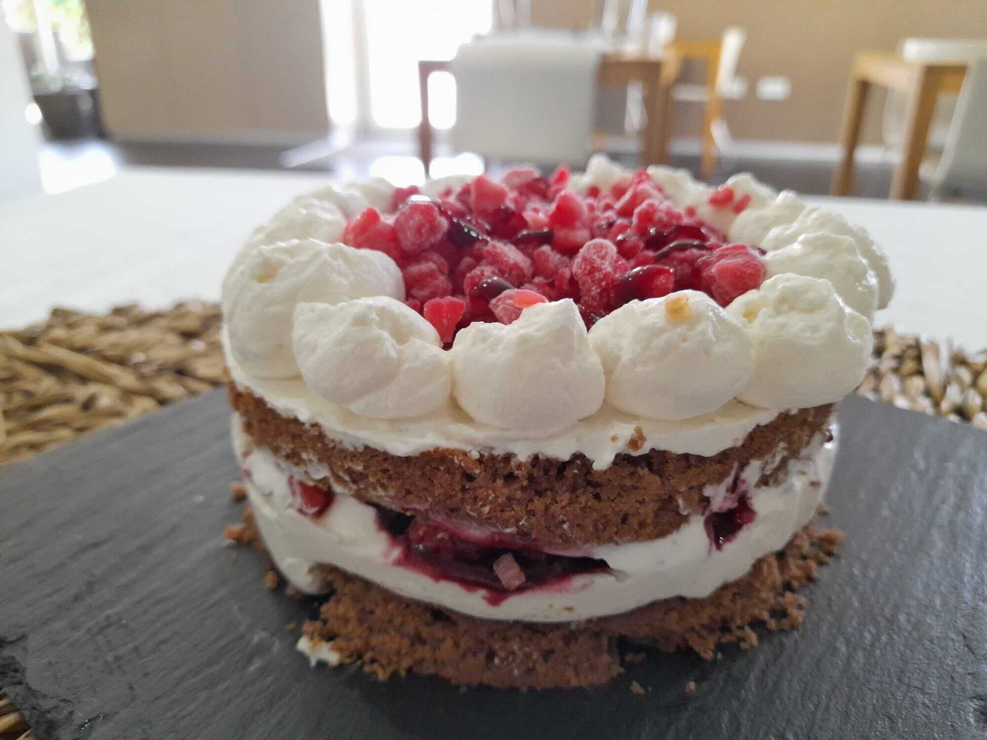 Sobremesa em camadas com chantilly e frutas vermelhas sobre um prato de ardósia.