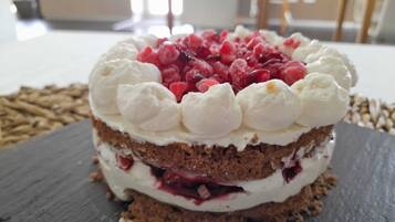 Sobremesa em camadas com chantilly e frutas vermelhas sobre um prato de ardósia.