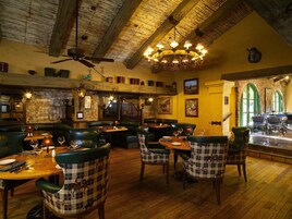 Restaurante com piso de madeira, assentos estofados verdes e um lustre.