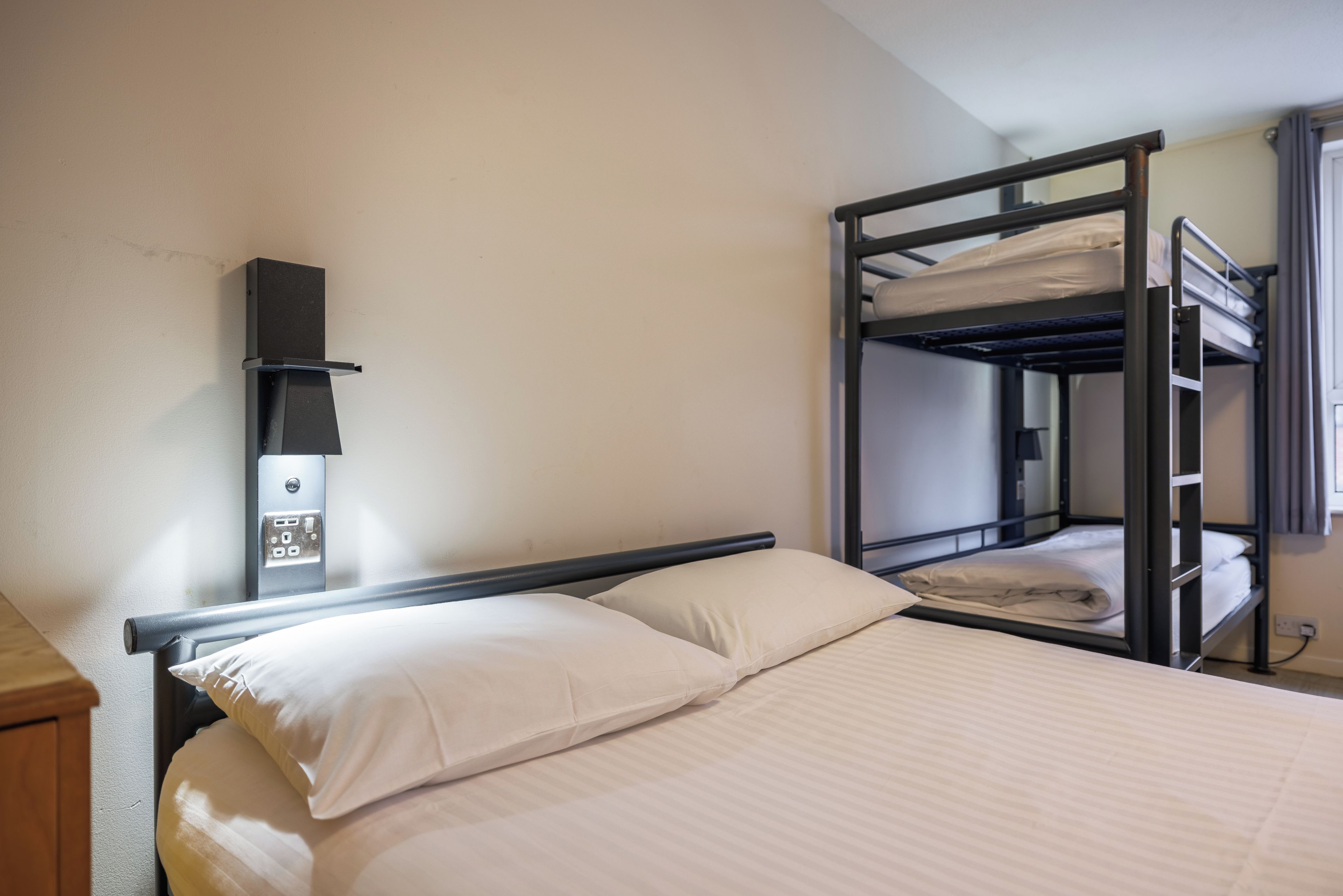 Uma cama beliche com escrivaninha dobrável e aquecedor fixado na parede.