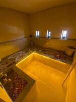 Um quarto de spa com banheira, pia pequena e janela com vista.