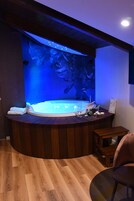 Uma área de spa com hidromassagem, piso de madeira e um espaço de estar com mesa e cadeiras.