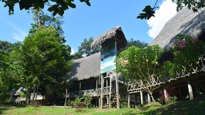 Um edifício tradicional com telhado de colmo, deck de madeira e uma placa.