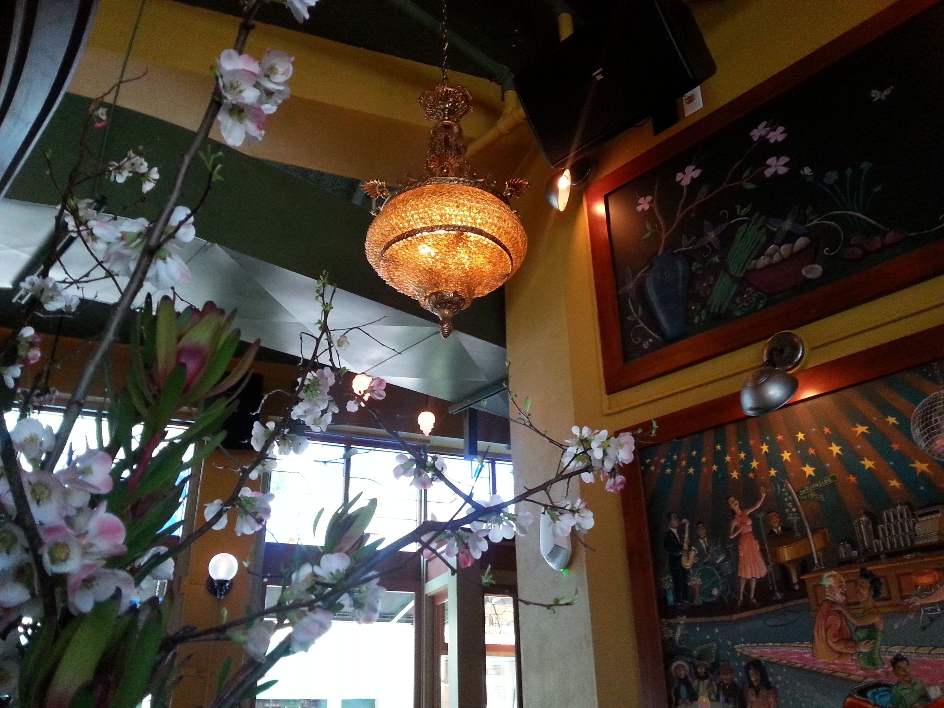 Um candelabro, um mural e um arranjo floral em um quarto com paredes verdes e amarelas.