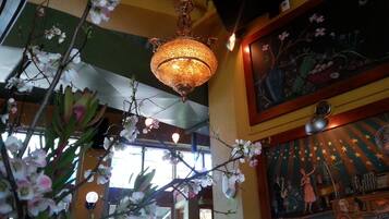 Um candelabro, um mural e um arranjo floral em um quarto com paredes verdes e amarelas.