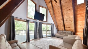 Amplo quarto tipo loft com uma grande janela, televisão de tela plana e teto de madeira.
