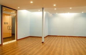 Quarto com piso de madeira, porta de vidro com puxador e parede azul claro.