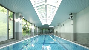 Piscina com claraboias, paredes de vidro transparente e piso revestido de azulejos.