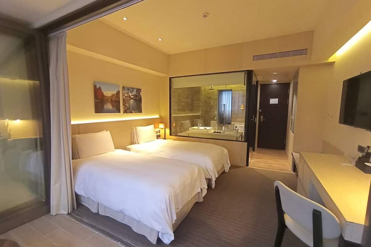 Quarto de hotel com uma cama, mesas de cabeceira, escrivaninha e espelho.
