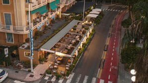 Restaurante com mesas ao ar livre, faixa de pedestres e ciclovia.