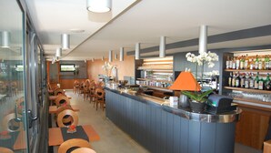 Uma área de bar moderna com um balcão comprido, assentos e diversas garrafas em prateleiras.