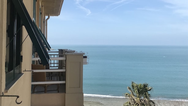Um edifício com varanda com vista para a praia.