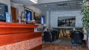 Uma sala de estar moderna com uma mesa de recepção de madeira, um quadro grande na parede e um vaso com planta.