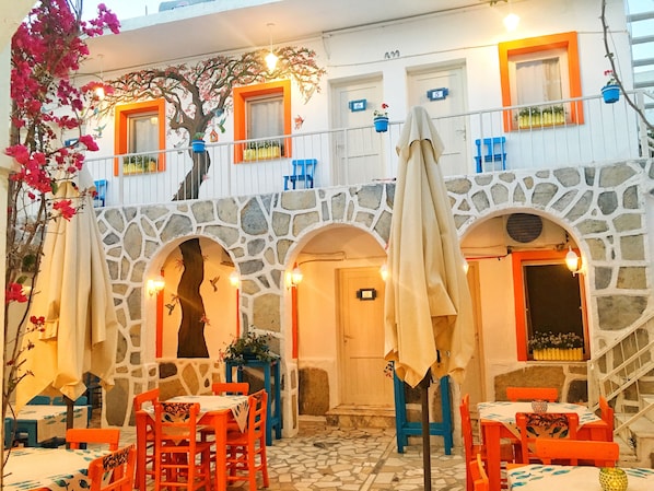 Restaurante com área externa, arcos de pedra e decoração colorida.
