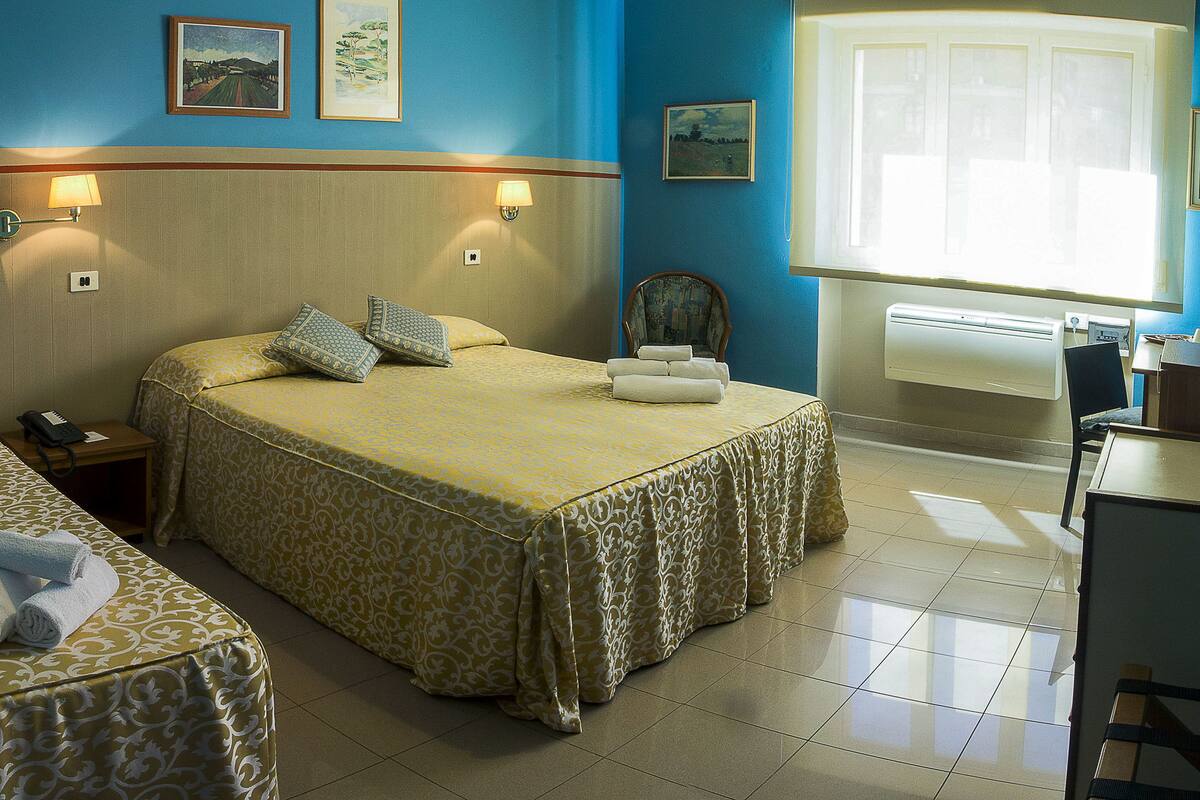 Quarto de hotel com duas camas, uma mesa e uma cadeira.