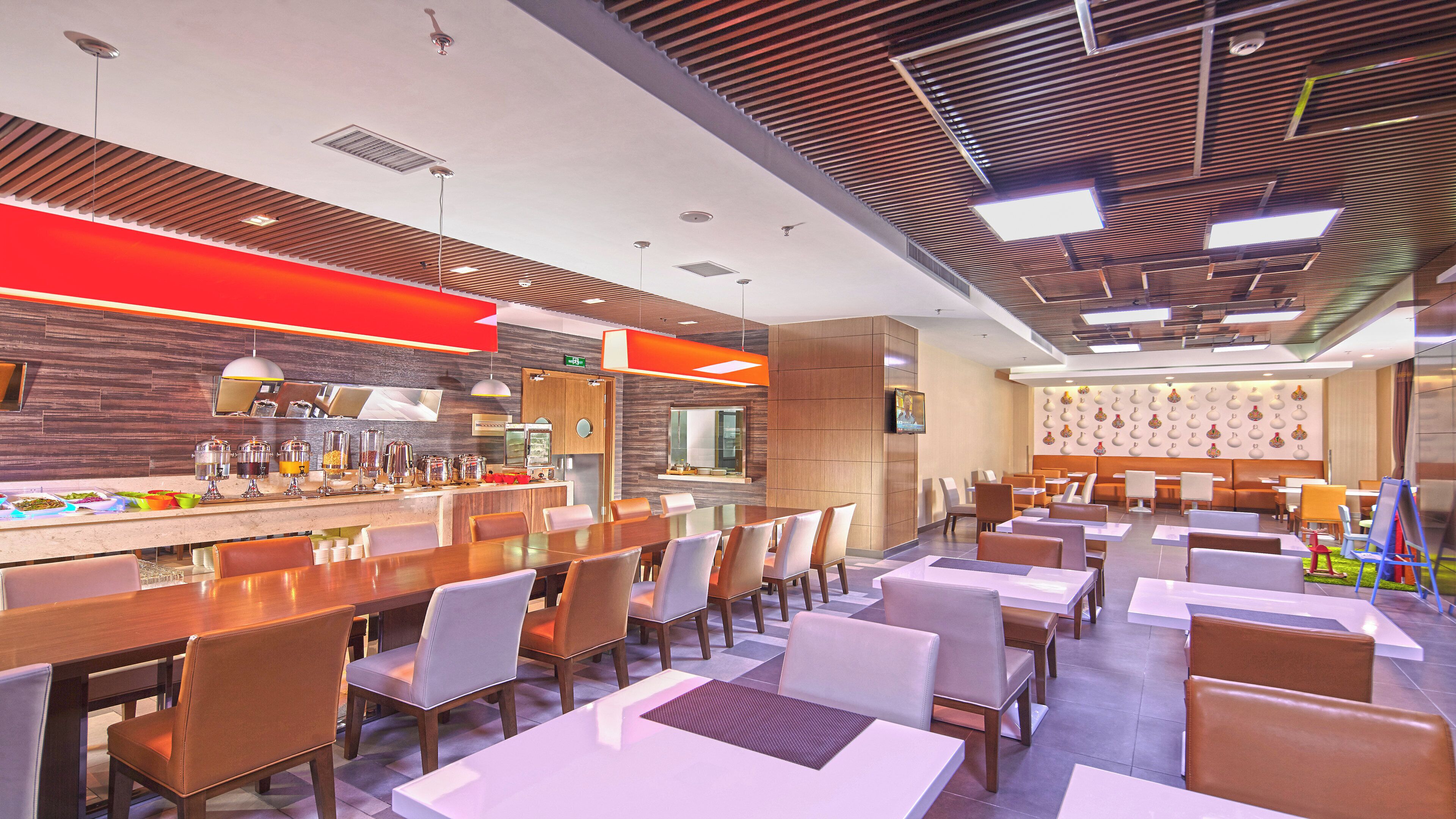 Um restaurante moderno com um balcão extenso, várias mesas e diversas opções de assentos.