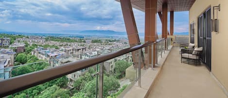 Varanda com grade de metal e vista para a cidade, com edifícios e áreas verdes.