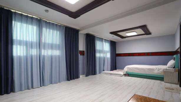 Quarto de hotel com uma cama grande, uma mesa de cabeceira e uma janela com cortinas.
