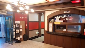 Uma área de recepção com balcão, vitrine de vidro e parede vermelha.