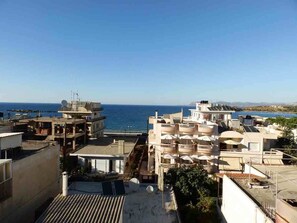 Zona residencial costeira com vários edifícios, alguns com varandas e antenas parabólicas, com vista para o mar.