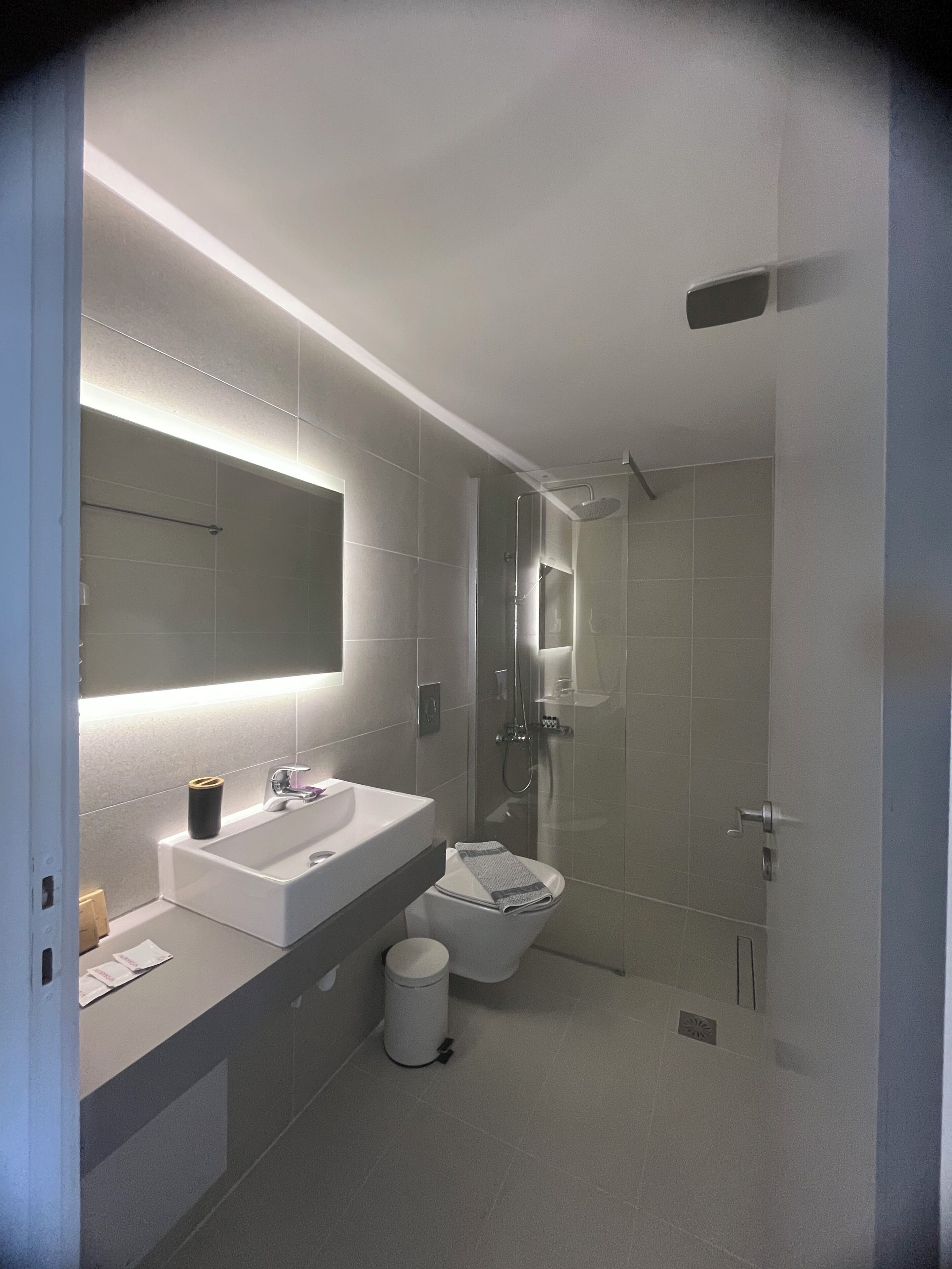 Uma casa de banho moderna com um espelho grande, duas bacias, sanita e chuveiro.