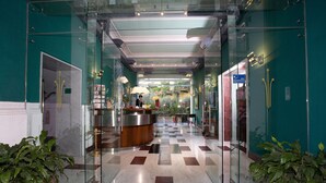 Um hall de hotel com balcão de recepção, mesa de check-in e divisória de vidro.