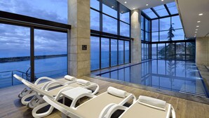 Piscina interior moderna com vista clara para o mar e para a paisagem urbana.
