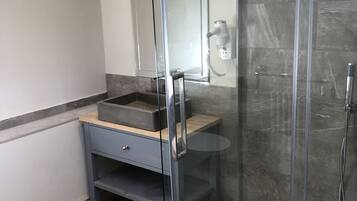 Uma casa de banho moderna com chuveiro de vidro, toucador de madeira e um espelho grande.