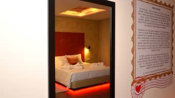 Quarto de hotel com uma cama, uma decoração em forma de coração na parede e um painel de texto na parede.
