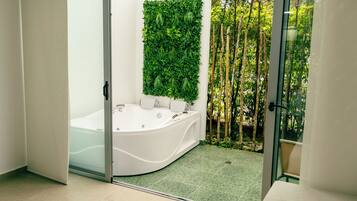 Um banheiro moderno com uma banheira grande e independente, um jardim vertical verde e vista para uma floresta por uma porta de vidro.