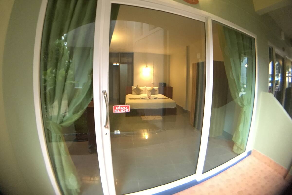 Quarto com uma cama, uma mesa de cabeceira e uma luminária fixada na parede.