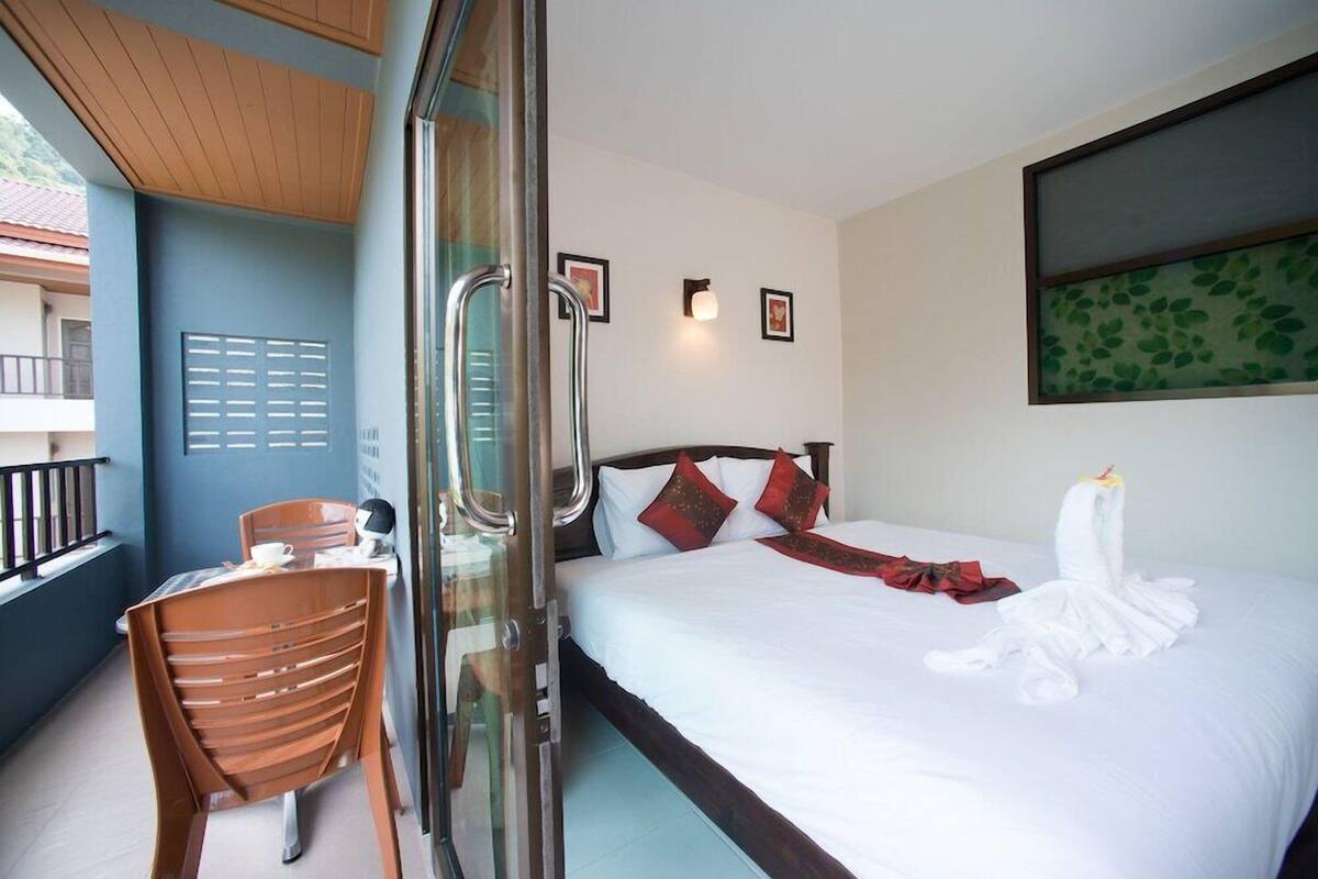 Quarto de hotel com cama, cadeira, porta de vidro e varanda.