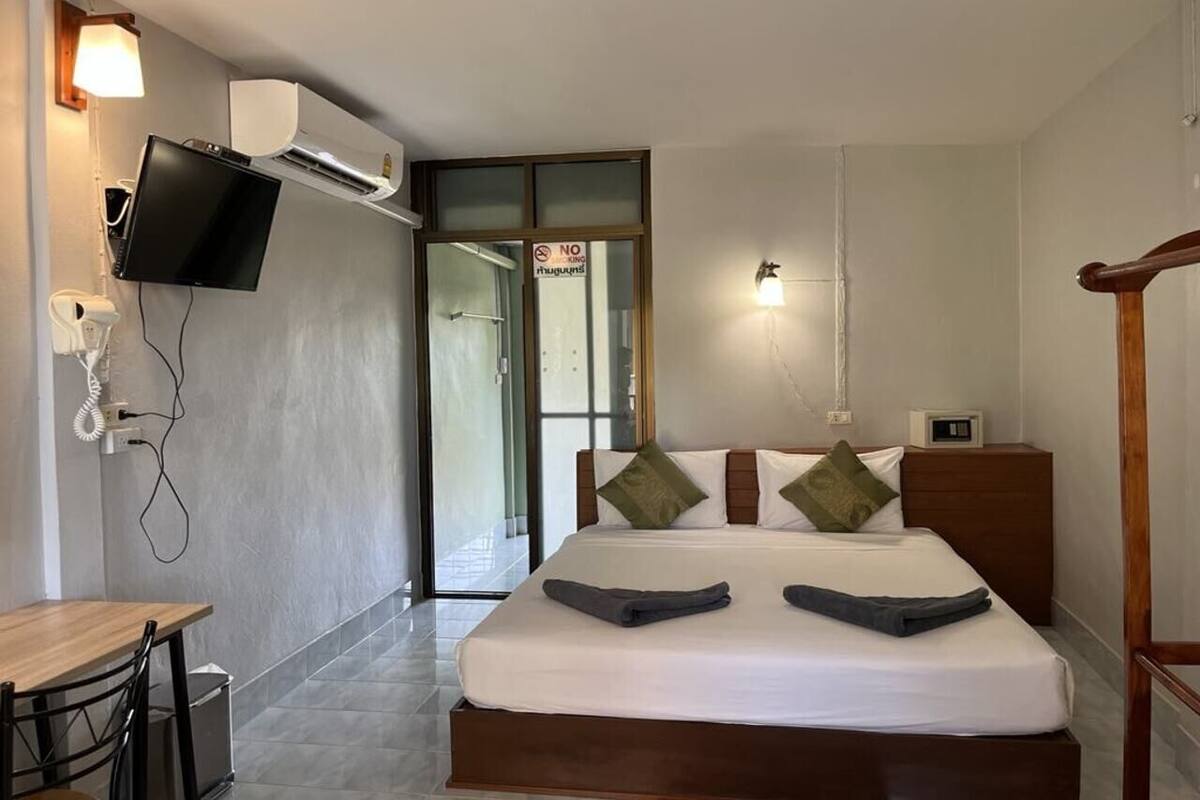 Quarto de hotel com cama, mesa de cabeceira, televisão e vista para o exterior.
