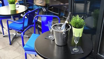 Uma mesa com uma garrafa de champanhe, um copo e um vaso de planta.